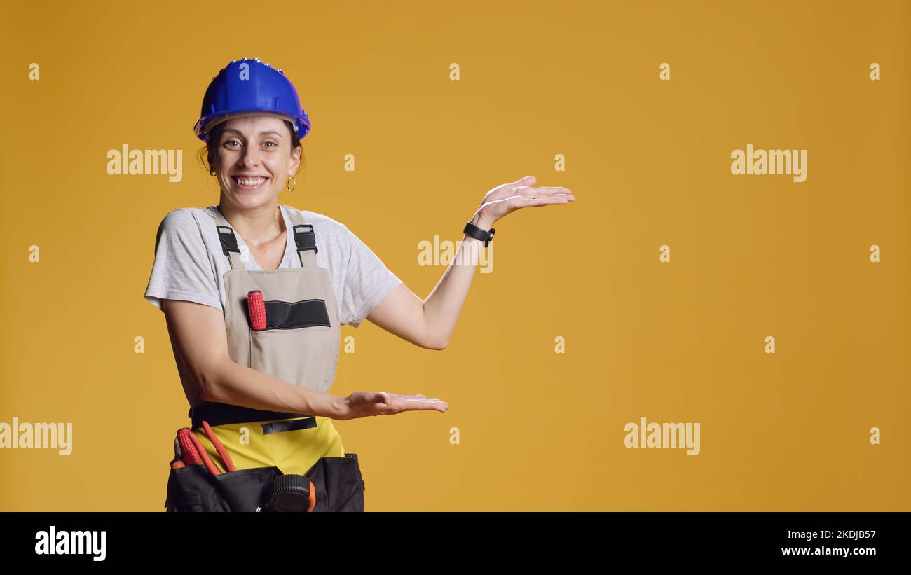 Portrait of construction worker advertising sideways space, pointing ...