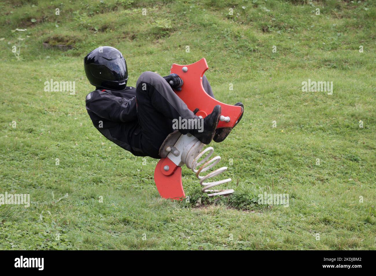 motorcyclist in black motorcycle clothing is sitting on a rocking horse ...