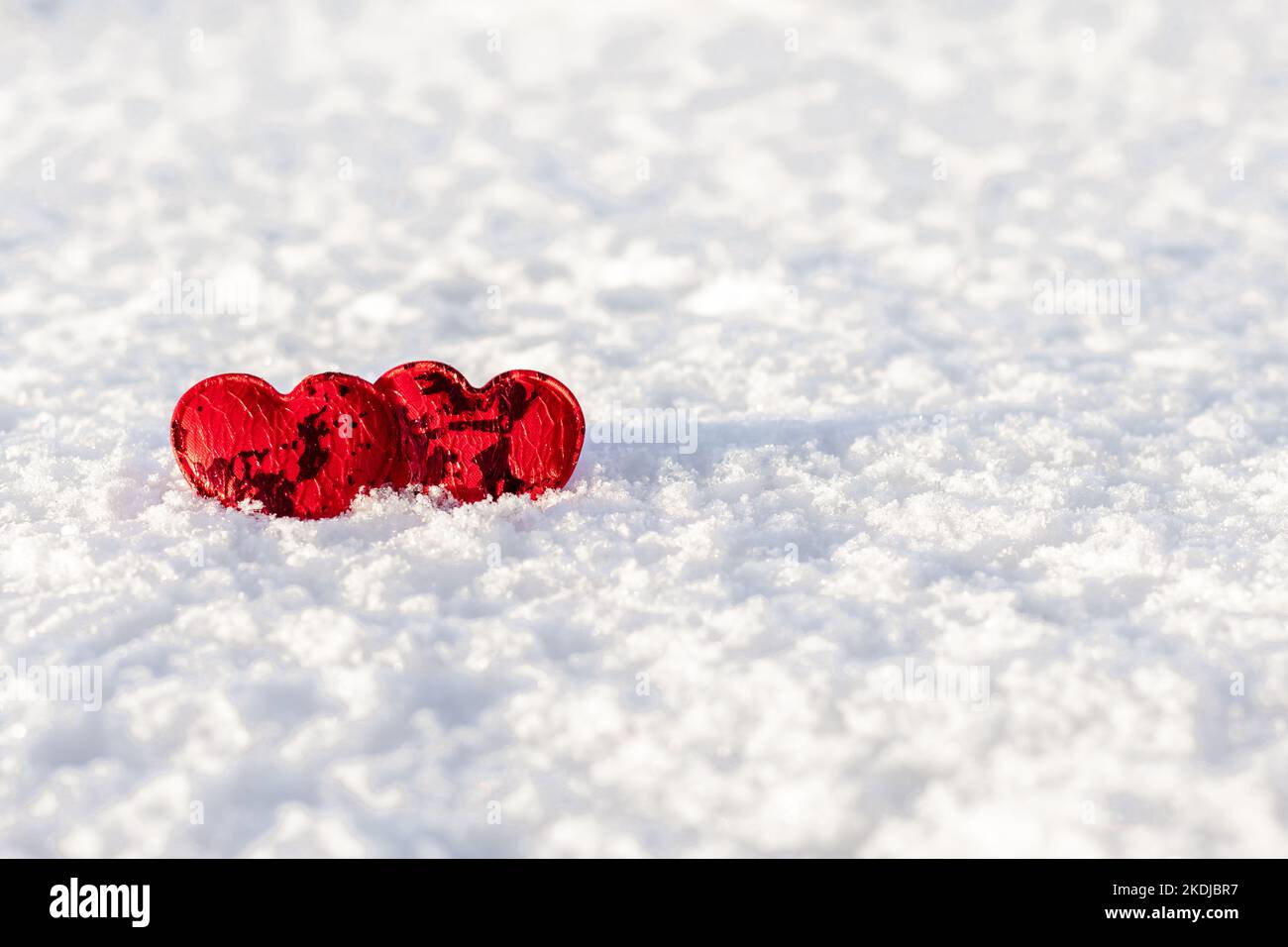 Two red hearts on a background of white snow. Place for an inscription ...