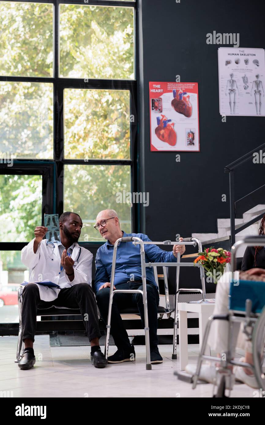 Practitioner medic looking at medical radiography with senior injured ...