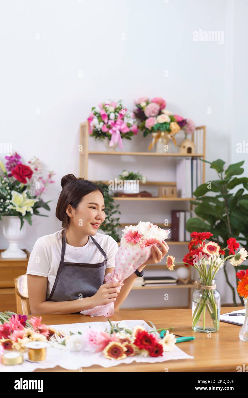 Flower shop concept, Female florist smile and holds colorful flower ...