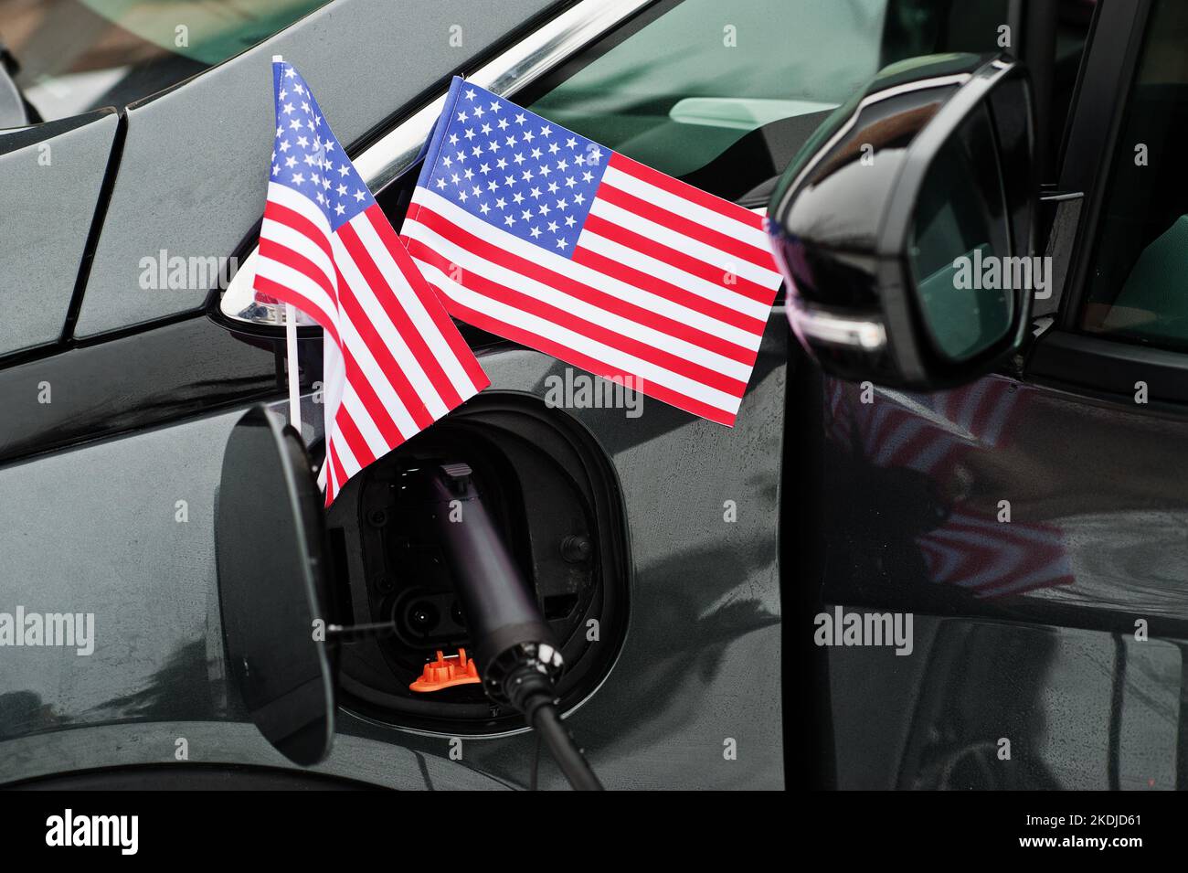 USA flag ecological car concept. Plugging a power supplier, charging ...