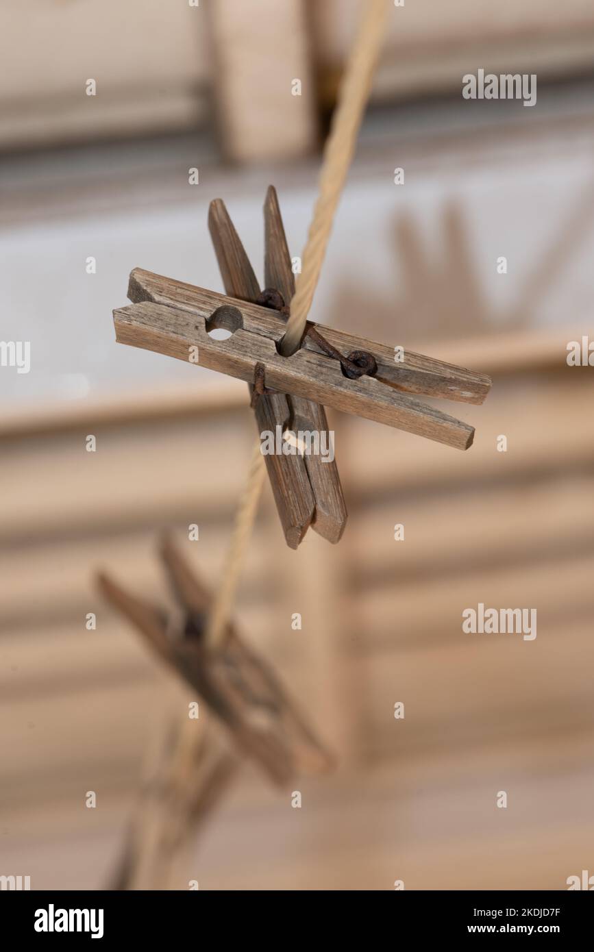 A line of old wooden clothes pegs on a nylon washing line with rusty ...