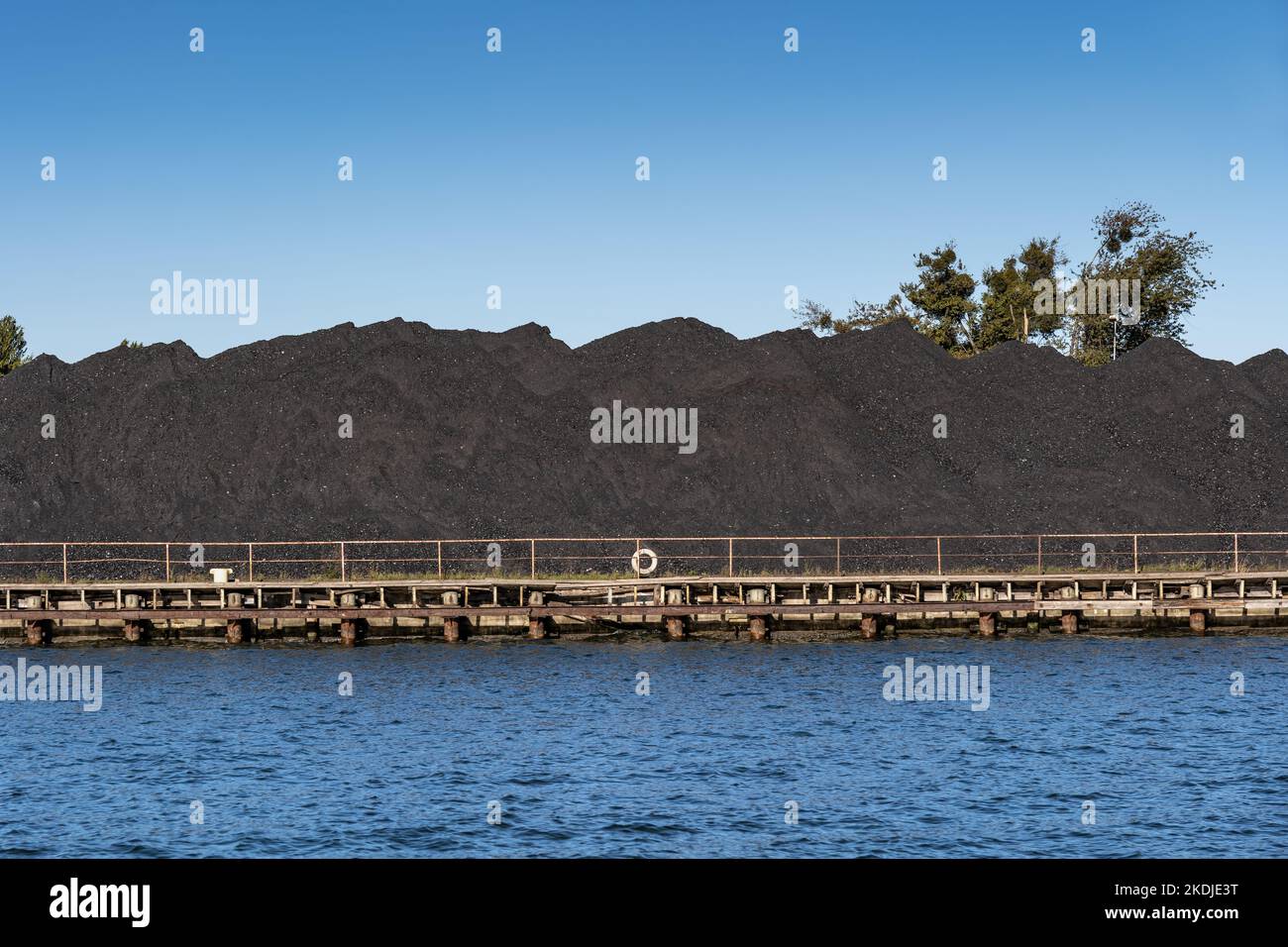 Piles of coal stacked at river waterfront, nonrenewable energy source ...