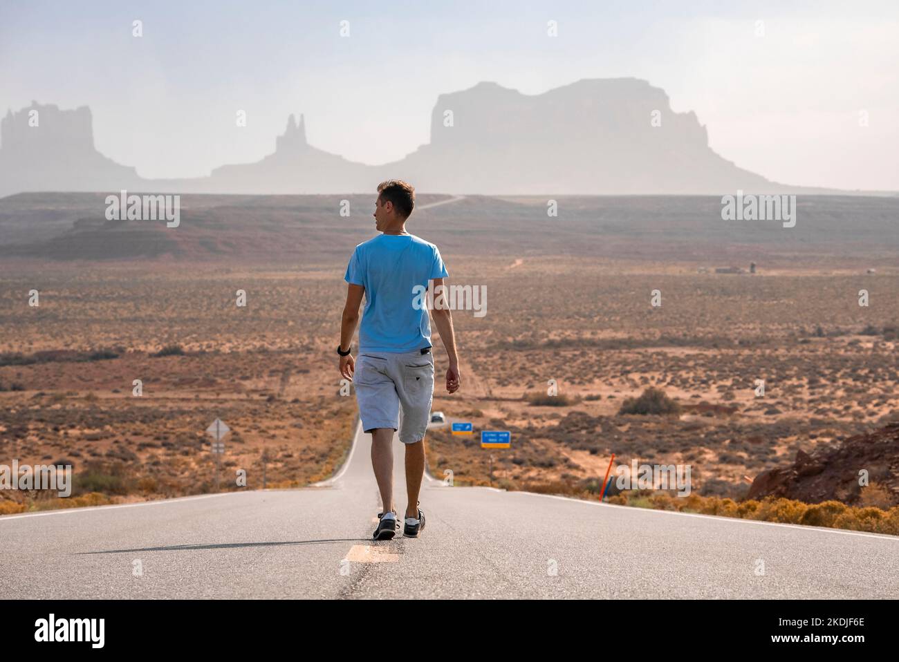 Rear view of young man walking on canyon road leading towards Monument ...