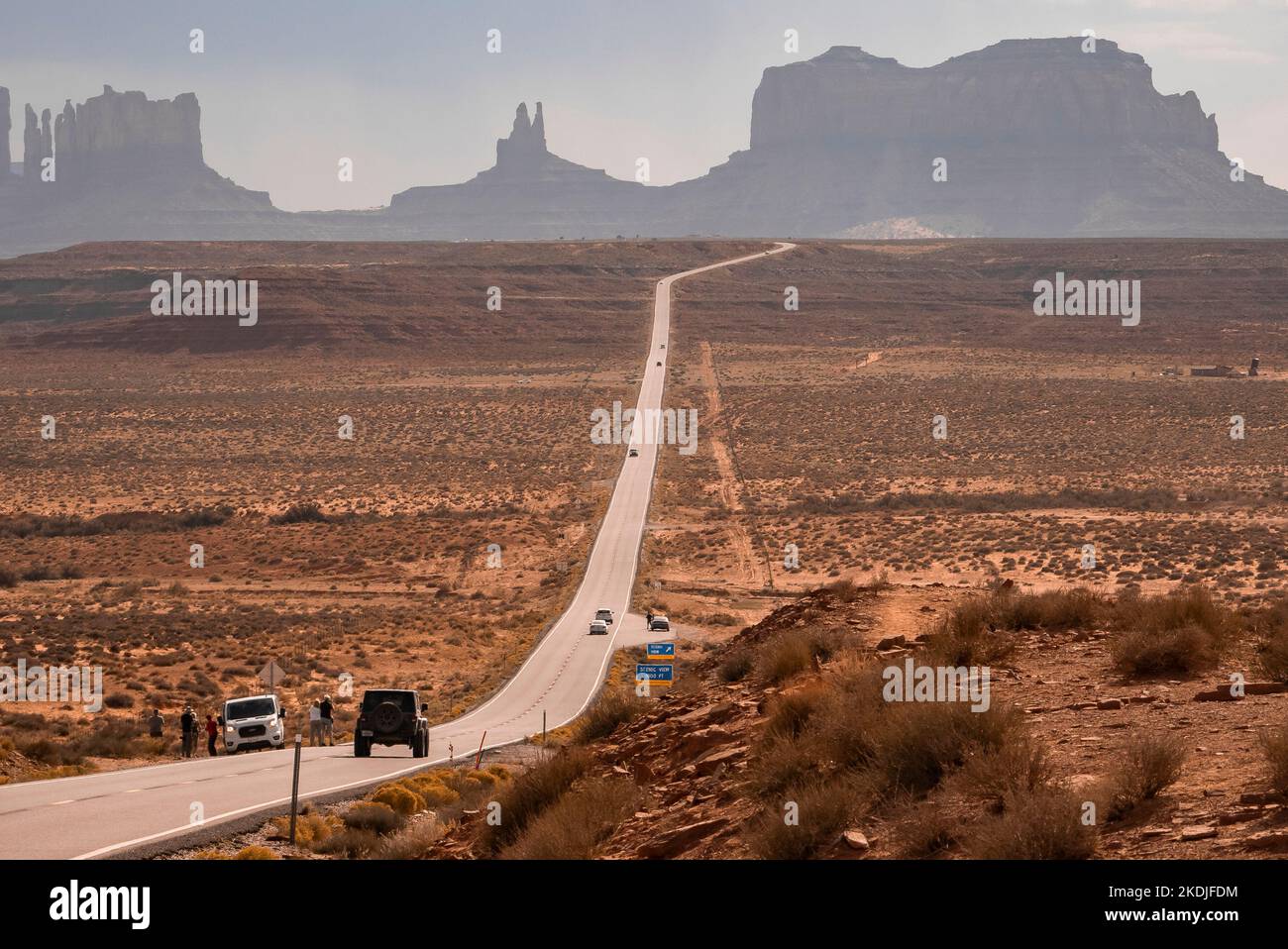 Cars on road amidst landscape leading towards Monument Valley during ...