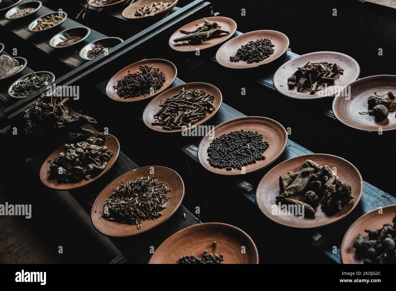 Various spices displaied on small ceramic and metal plates on black ...