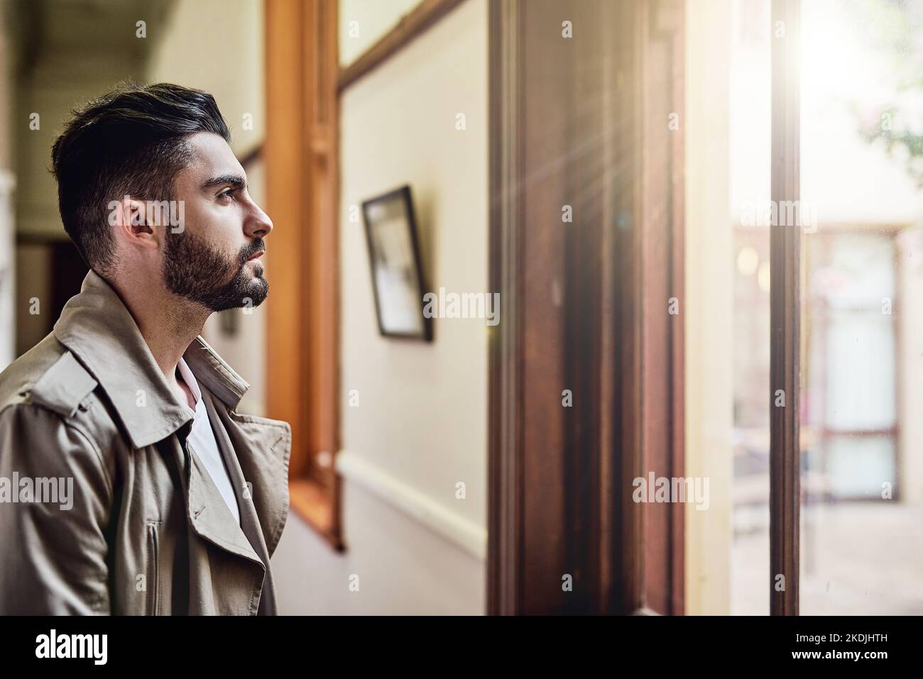 Taking in the day from his window. a handsome young man standing by a ...