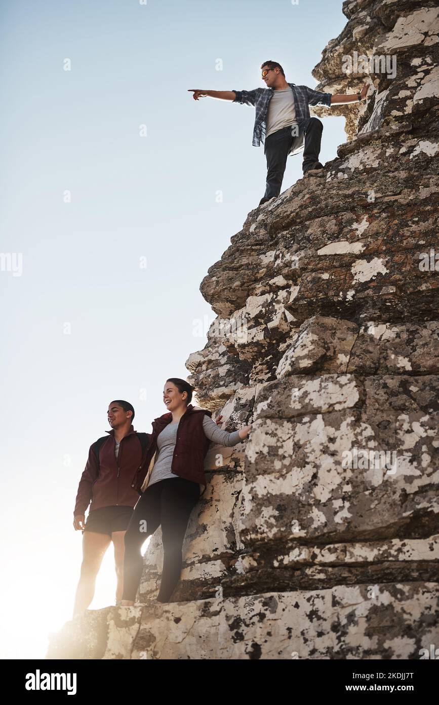 Its over there. a young man pointing something out to his friends while ...