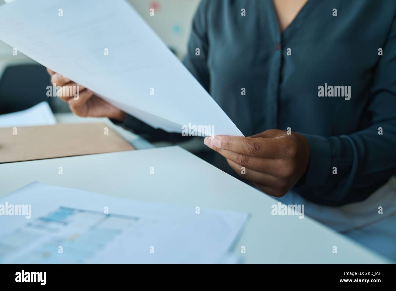 Woman sits table and holds sheet of paper in her hands Stock Photo - Alamy