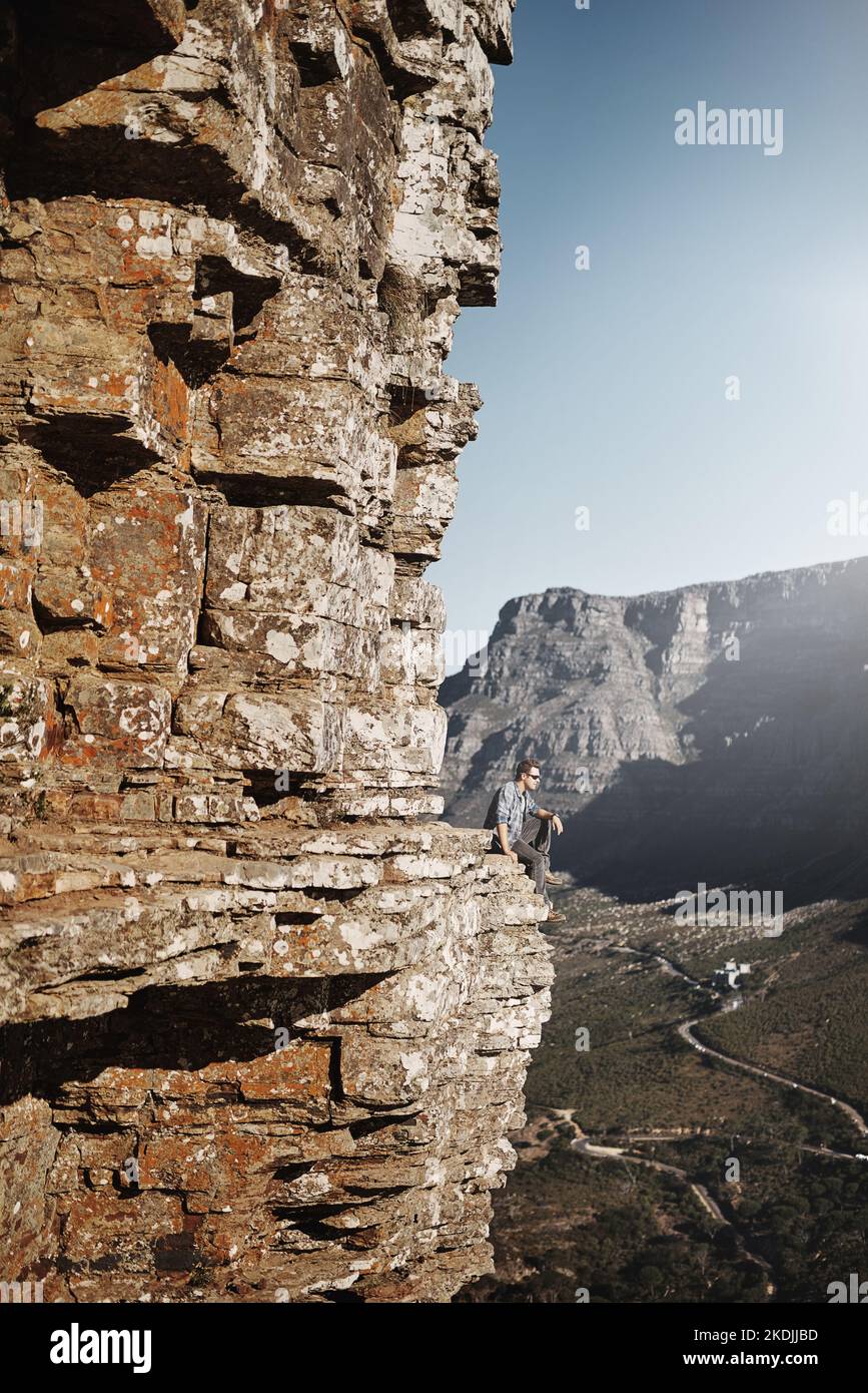 Taking in a magnificent view. a young man sitting on the edge of a ...