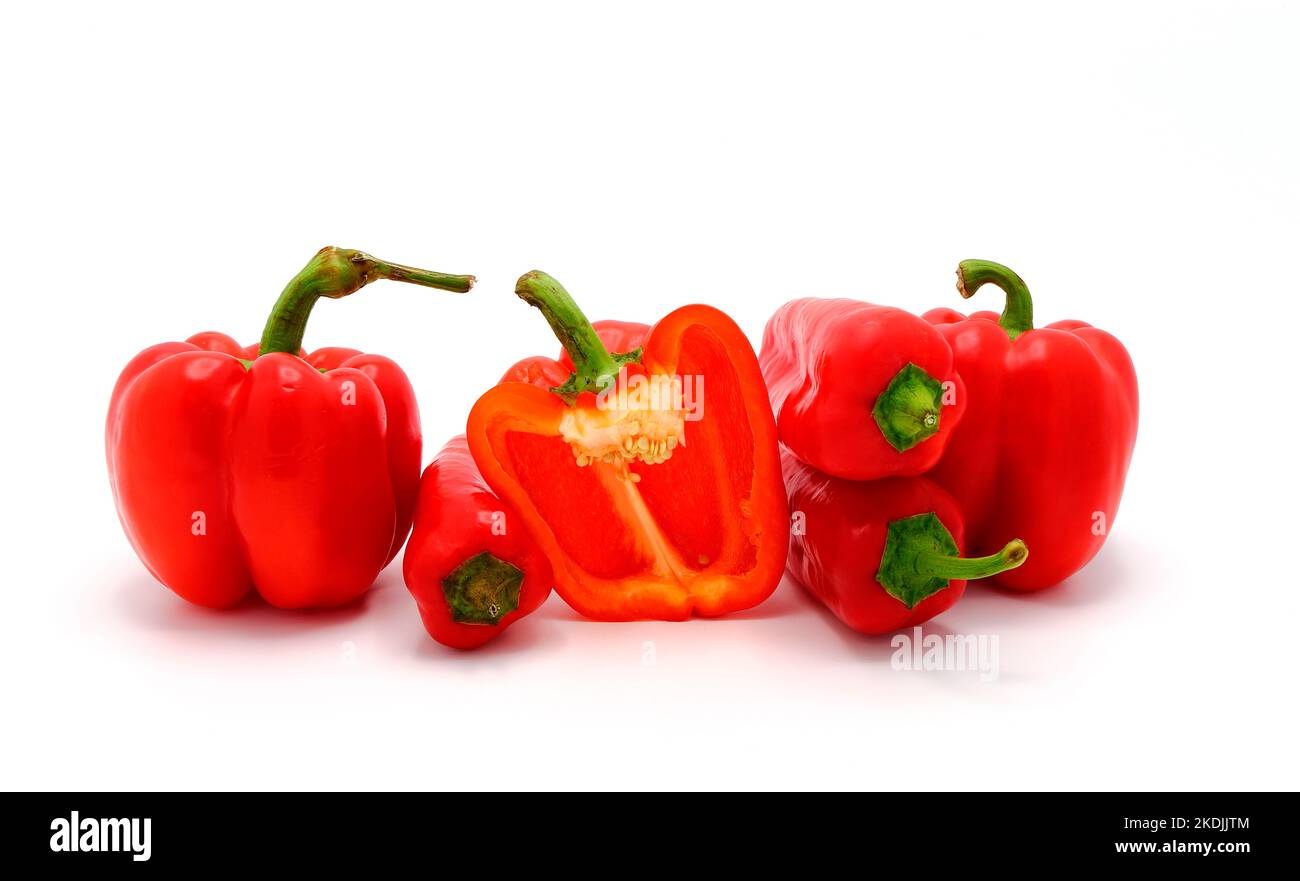 Few red ripe sweet peppers and one pepper in a cut on a light ...