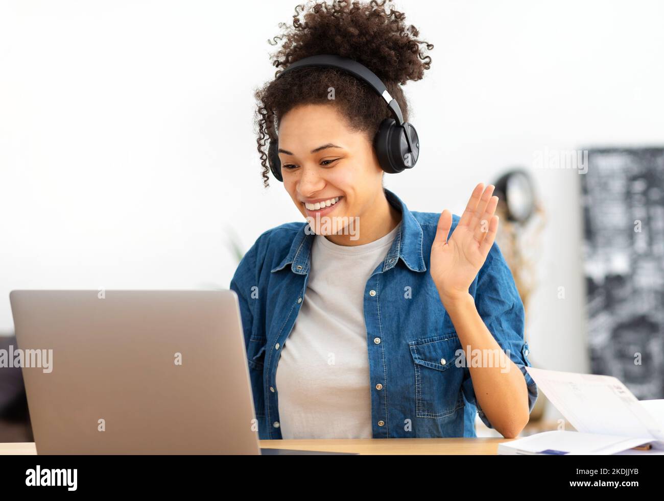 Happy African American female student in headphones using laptop ...