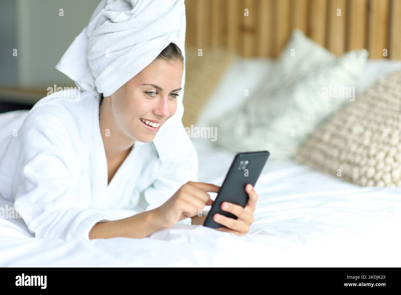Happy teen after showering with a towel over head using cell phone on a ...