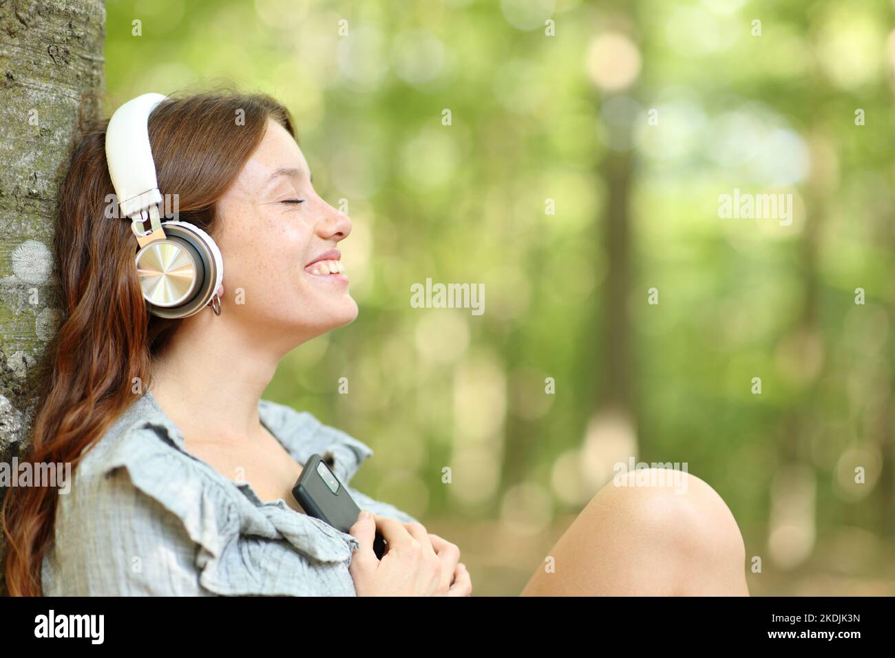Side view portrait of a happy woman listening to music with headphones ...