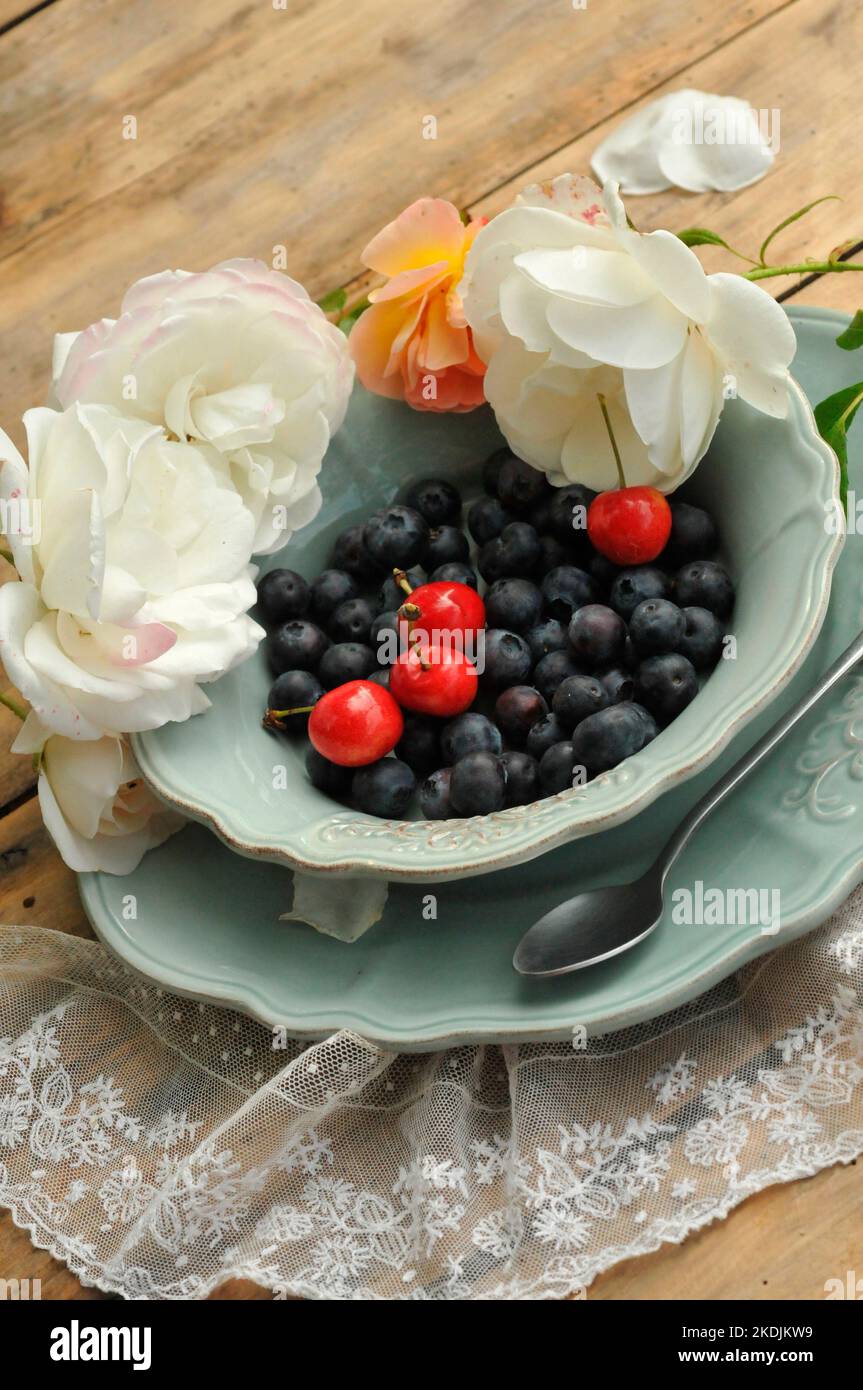 Blue plate full of blueberries and cherries from the garden, flowered ...