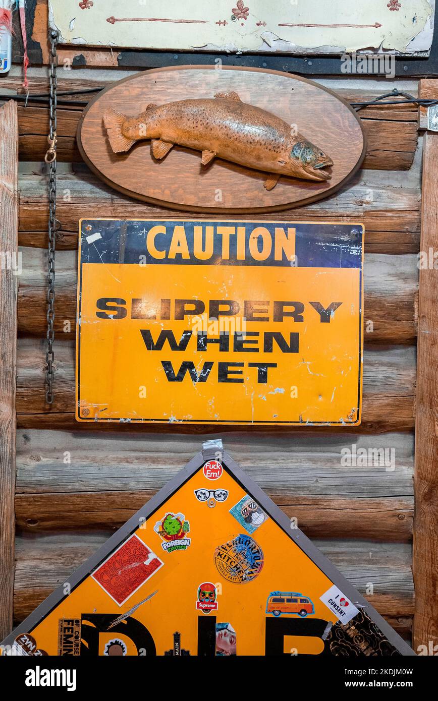 Caution sign and fish sculpture mounted on wooden wall at restaurant ...