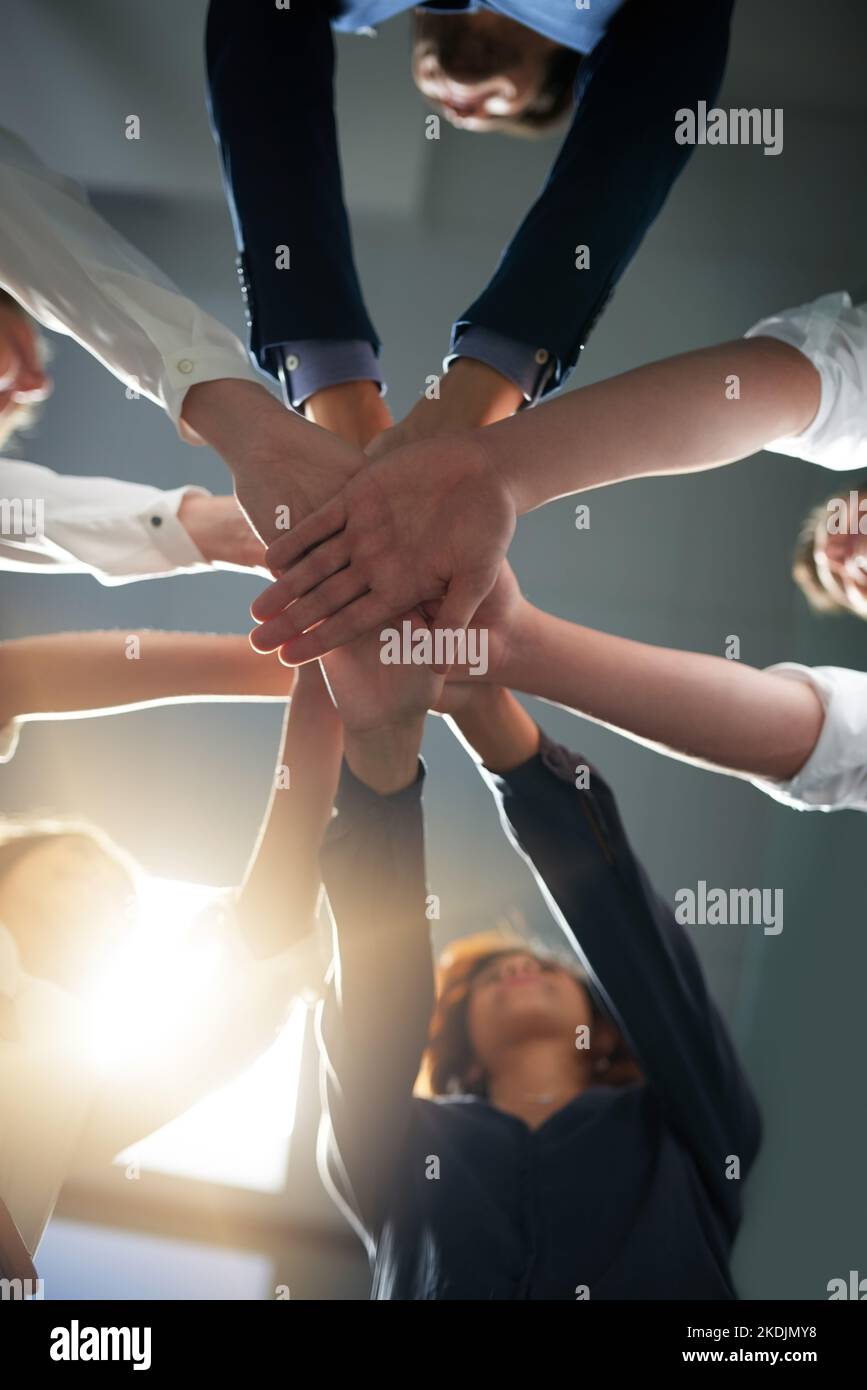 We can and we will. a group of businesspeople joining their hands ...