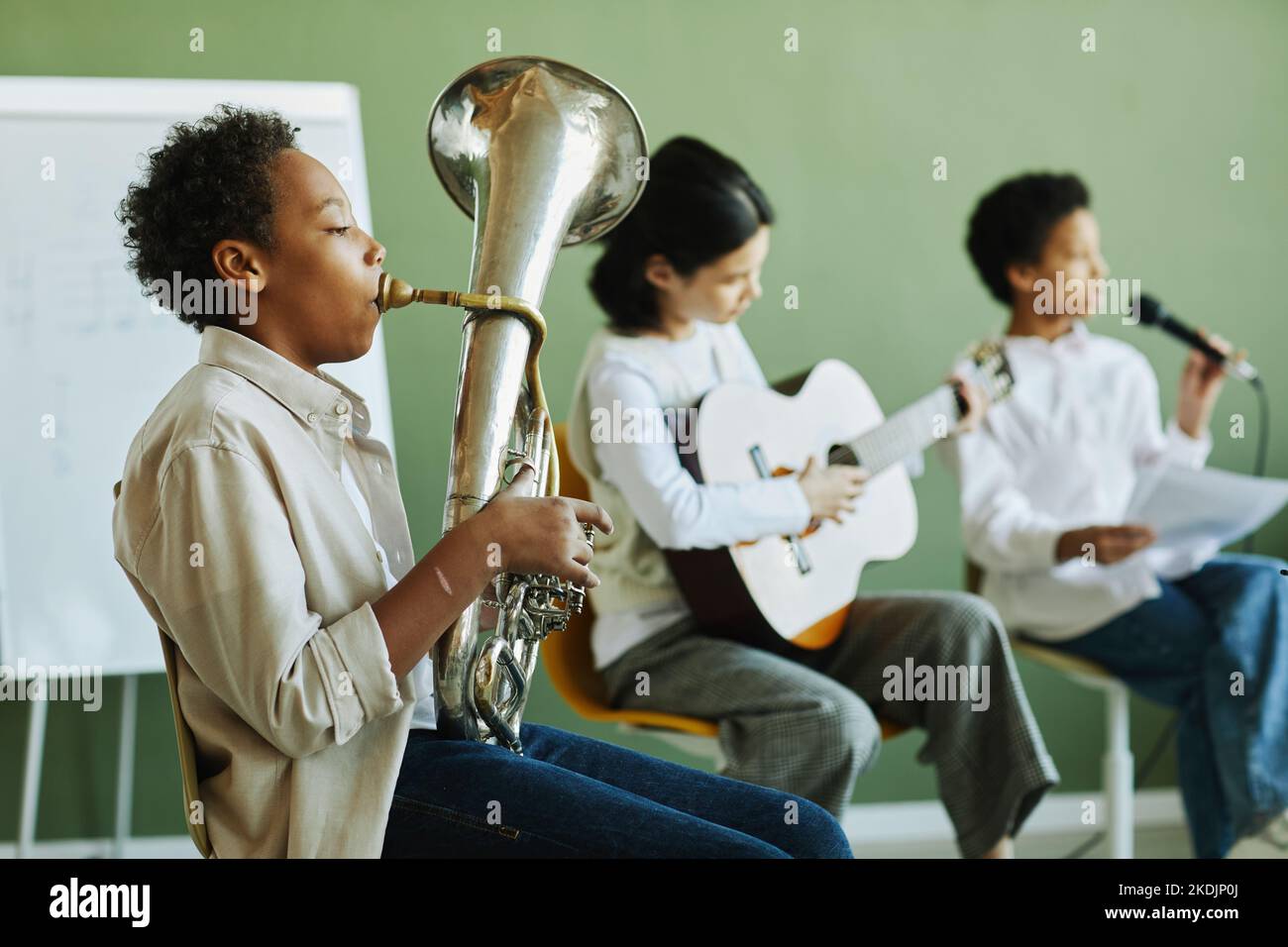 Cute African American schoolboy blowing trumpet against two ...