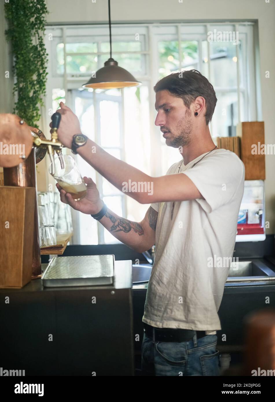 Pouring at the perfect angle. a young bartender pouring beer from a tap ...