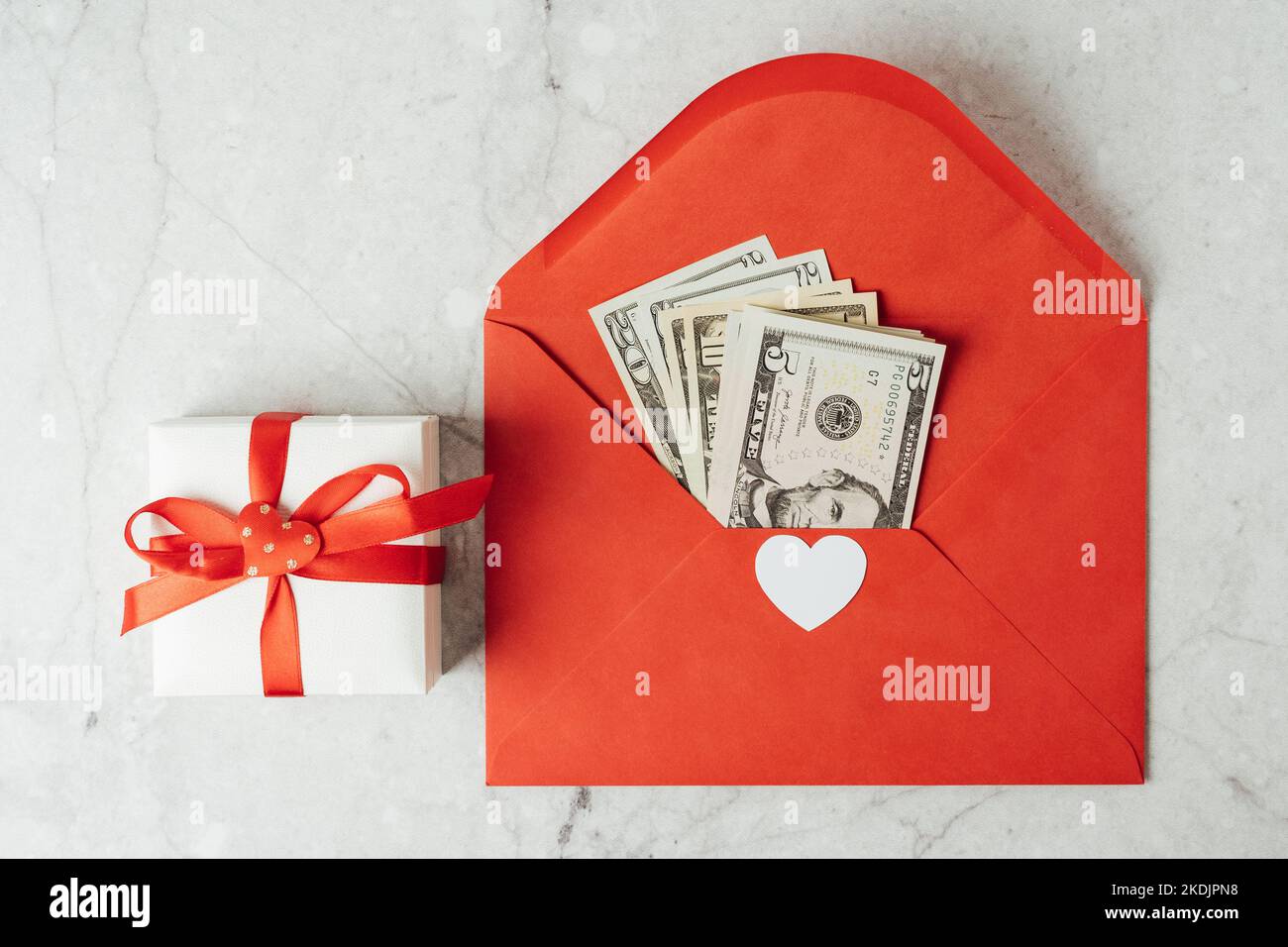 Red paper envelope with money dollars bills. Flat lay of gray working ...