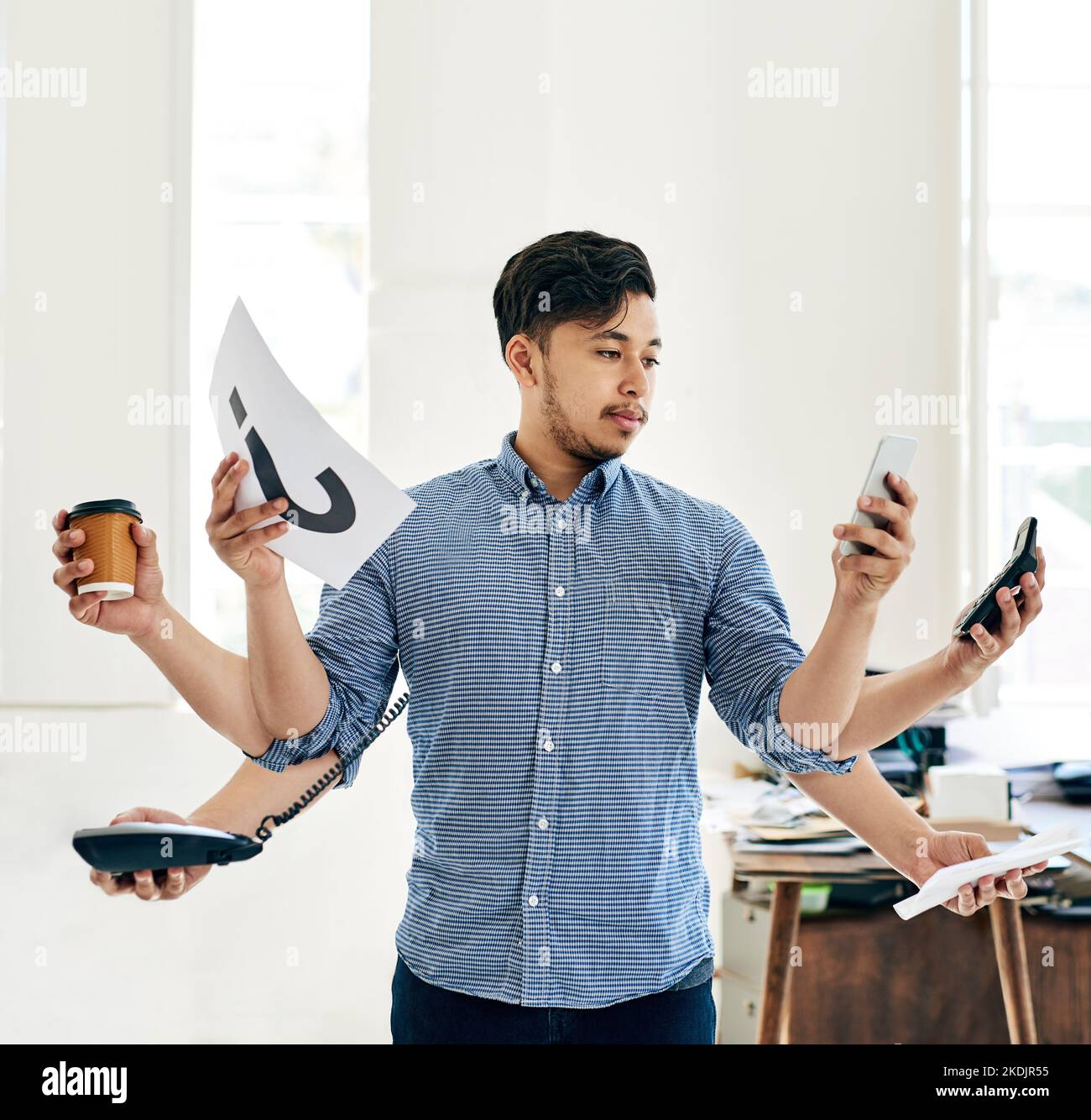 Many hands make business work. a young entrepreneur multitasking at ...