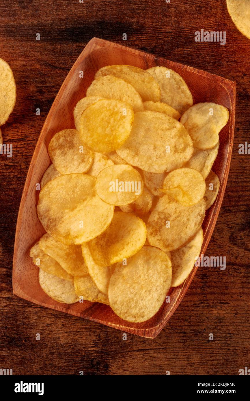 Potato chips or crisps, a salty snack in a wooden bowl, top shot on a ...