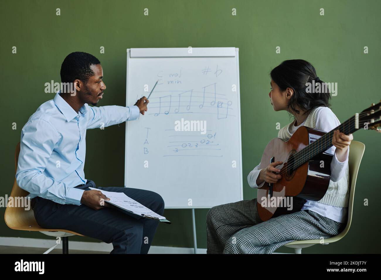 Side view of confident teacher of music explaining musical notes to ...