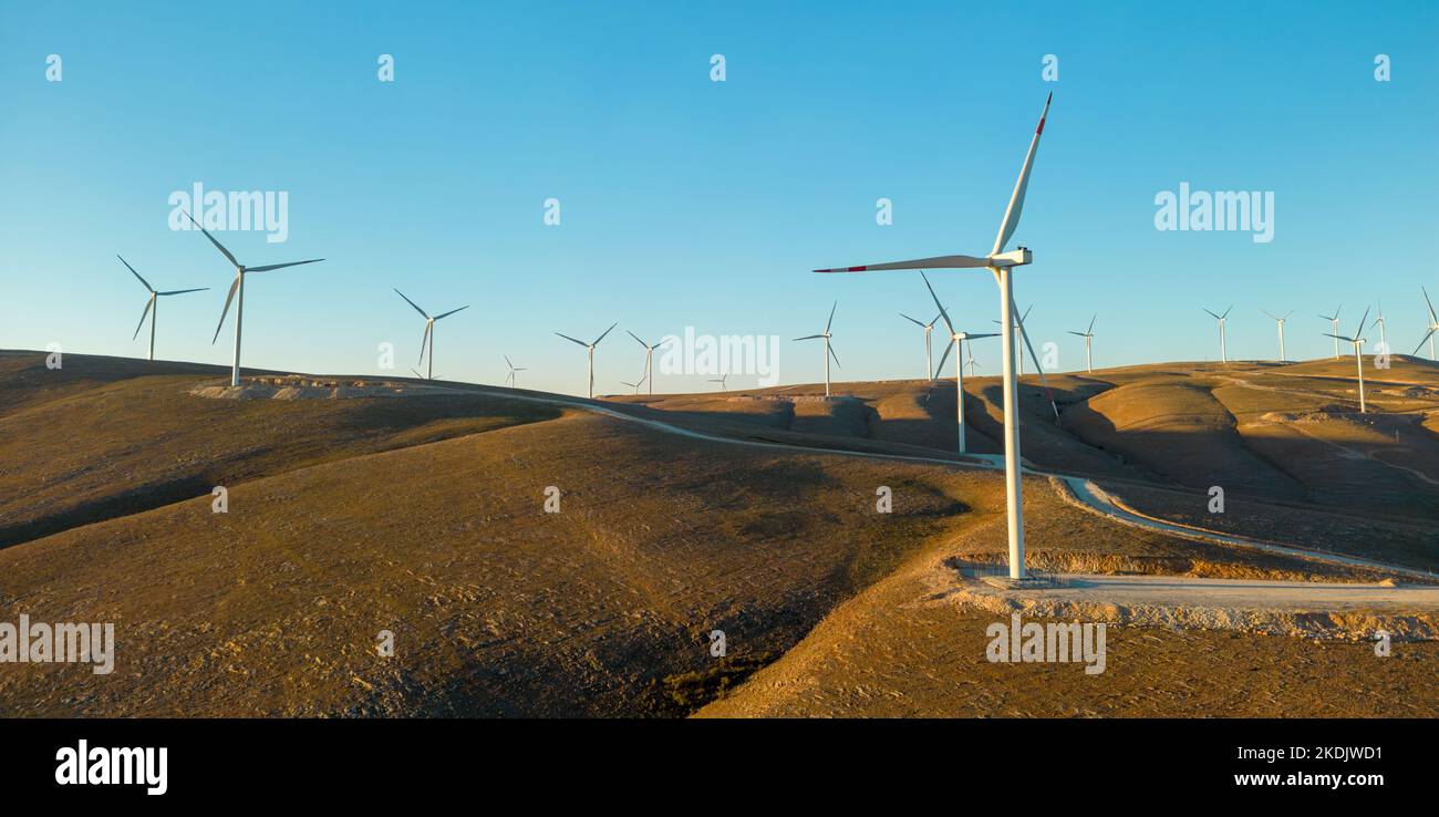 Aerial view of multiple wind turbines standing on a hill and generating ...