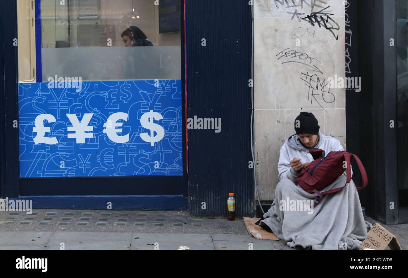 London, UK. 21 October, 2022. A homeless man sits next to a currency ...