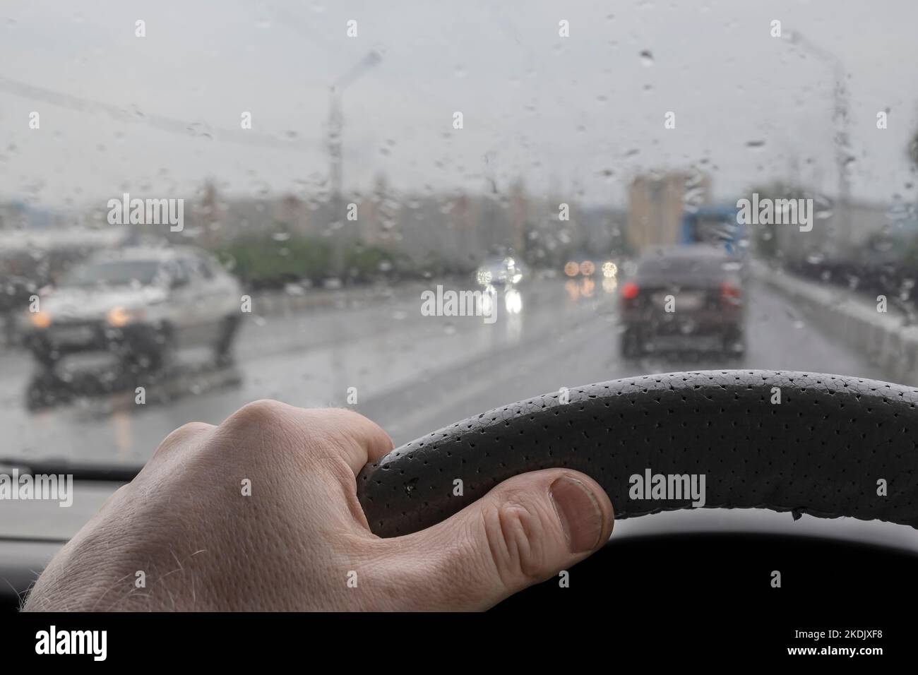 driver hand behind the wheel of a car against the background of a wet ...