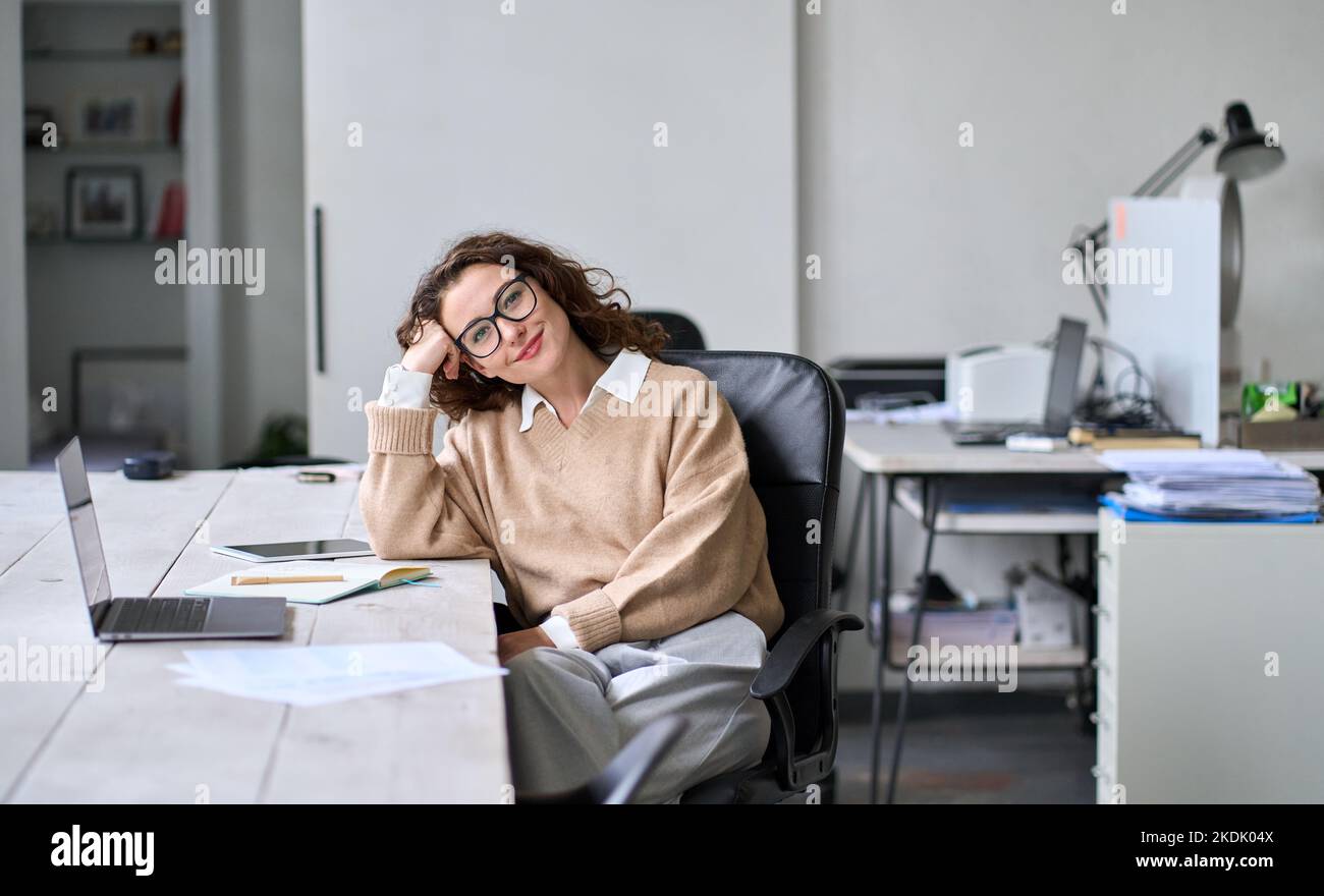 Young happy relaxed professional business woman sitting at work desk ...