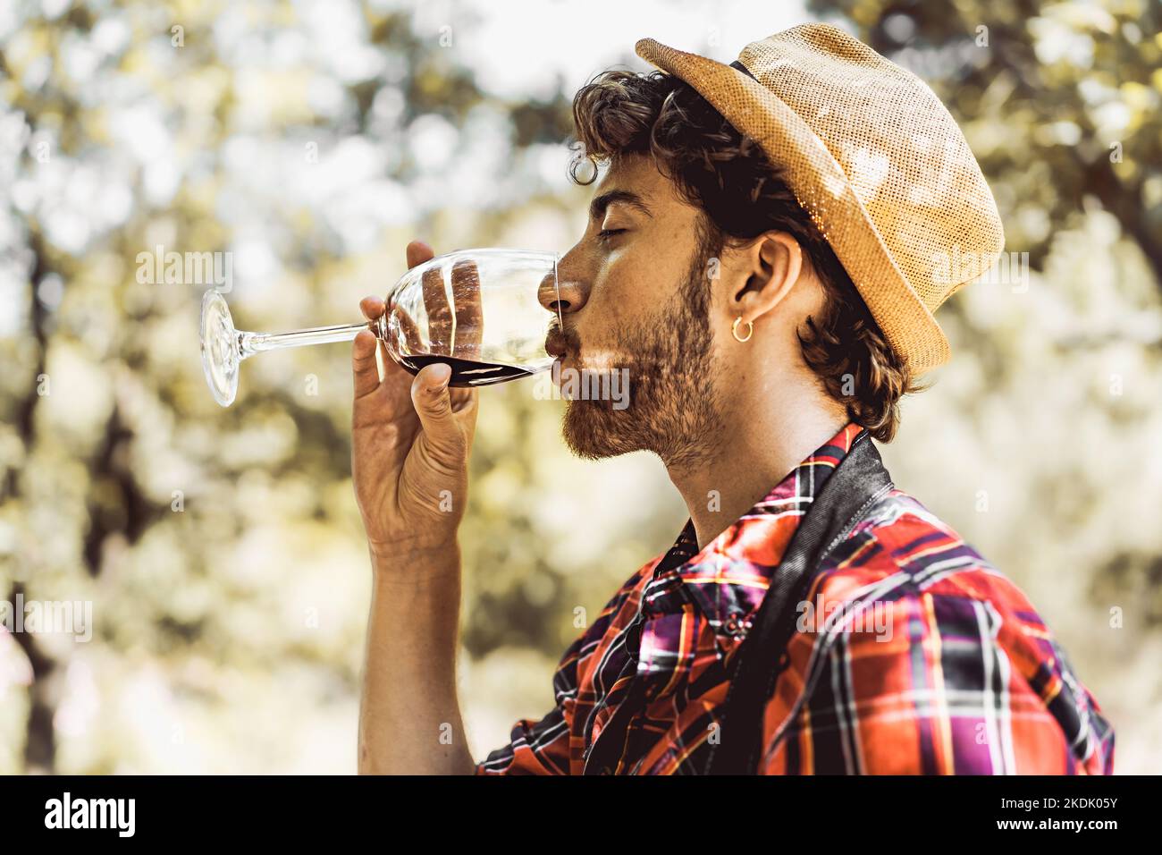 Handsome bearded guy drinking red wine at the grape harvest picnic ...