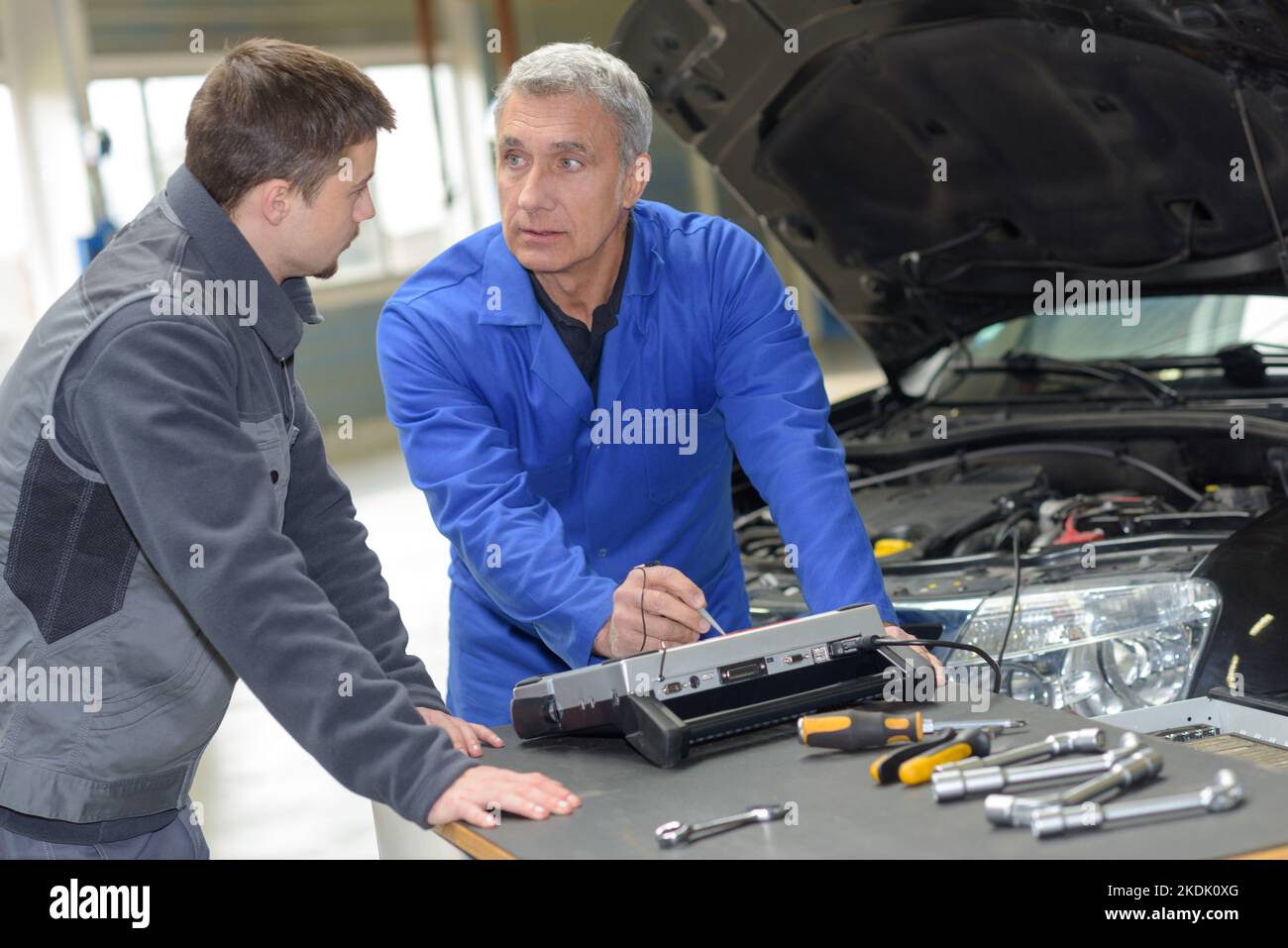 auto mechanic teacher and trainee performing tests at mechanic school ...