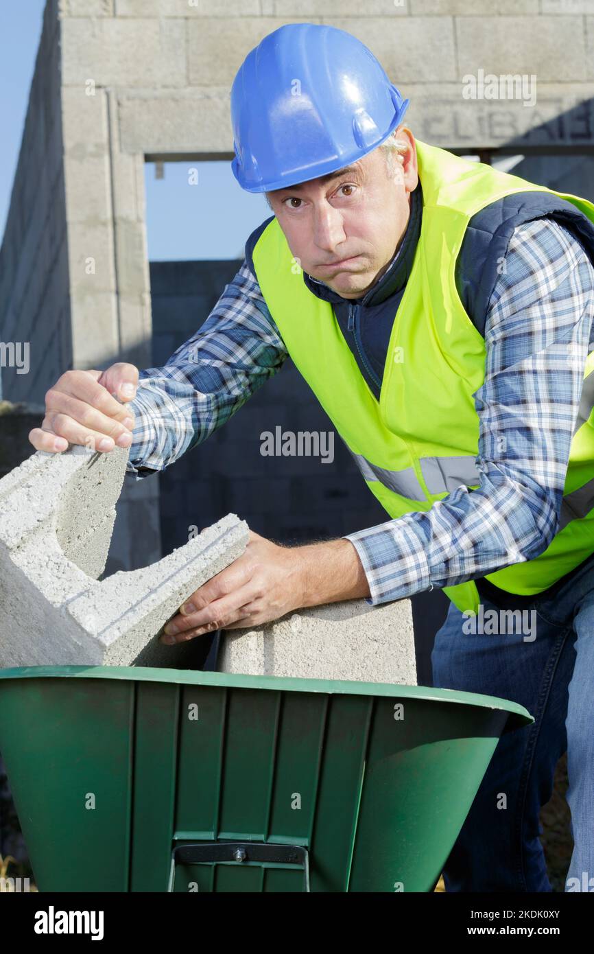 bricklayer putting bricks on wheelbarrow Stock Photo - Alamy