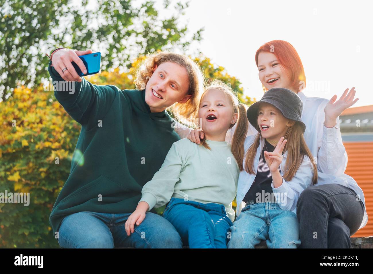Portraits of three smiling sisters and brother teen taking selfie ...