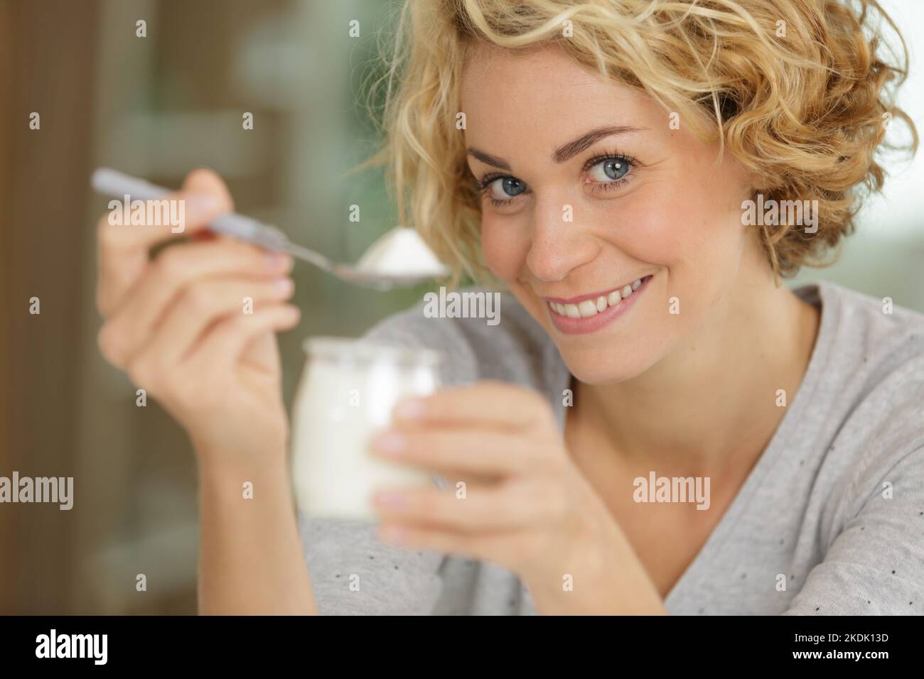 a woman eating yogurt smiling Stock Photo - Alamy