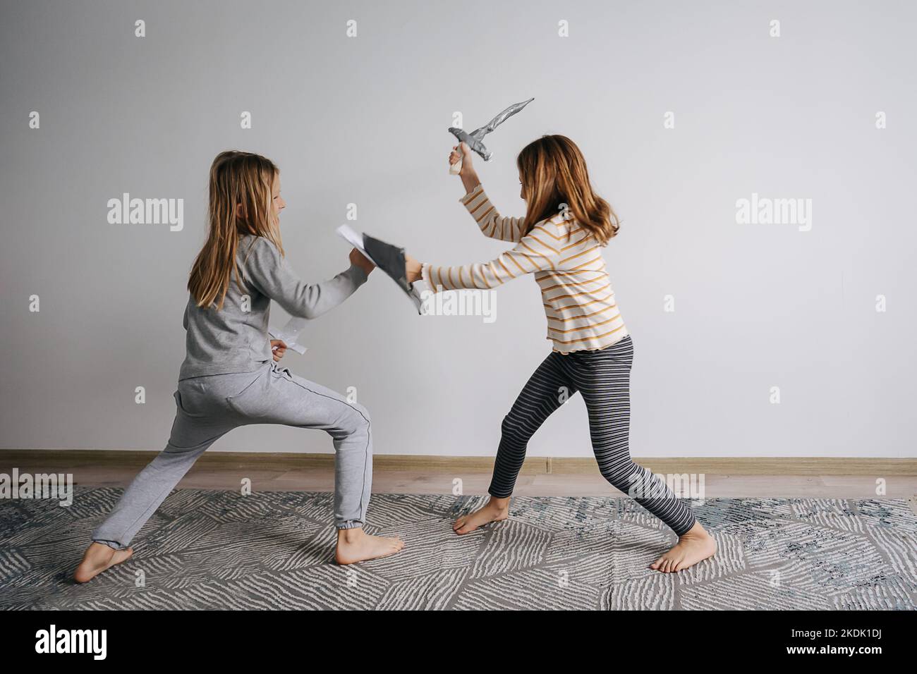 Girl and boy battling with self-made toy paper swords and shields ...