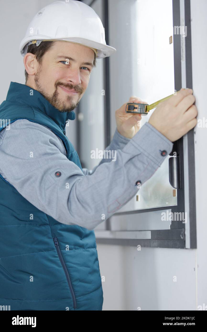 young engineer using tape measure for measuring window at site Stock ...