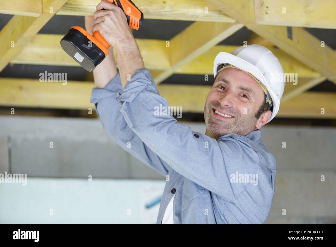 happy construction man using a drill to secure a beam Stock Photo - Alamy
