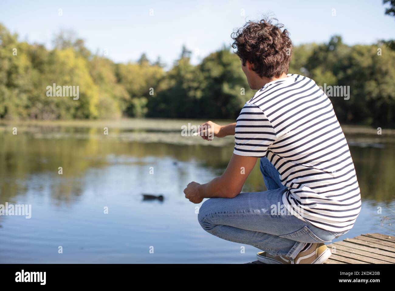 a young man sitting near a nice lake Stock Photo - Alamy