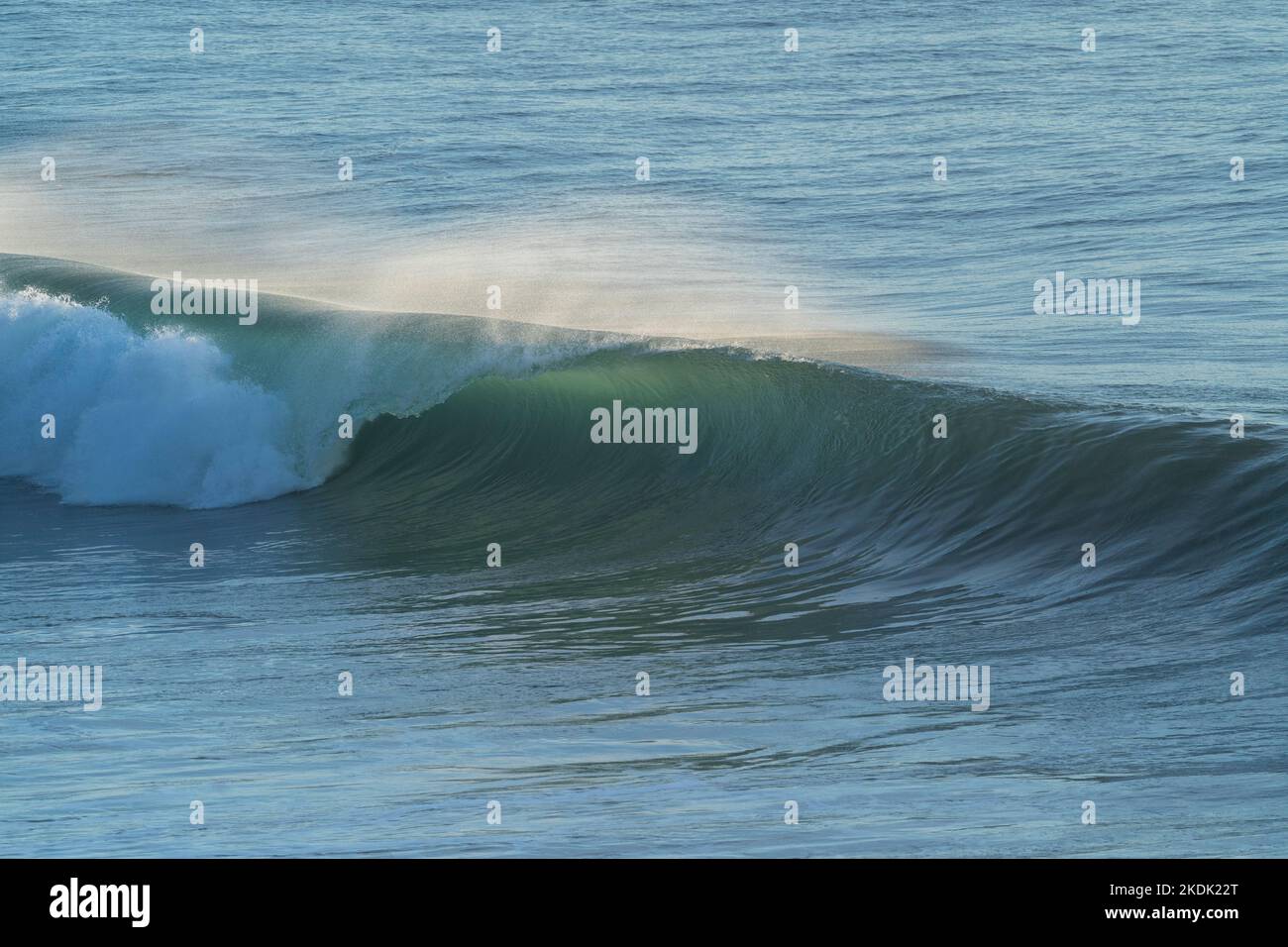 Perfect wave breaking on a offshore wind bright sunny day on a sandy ...