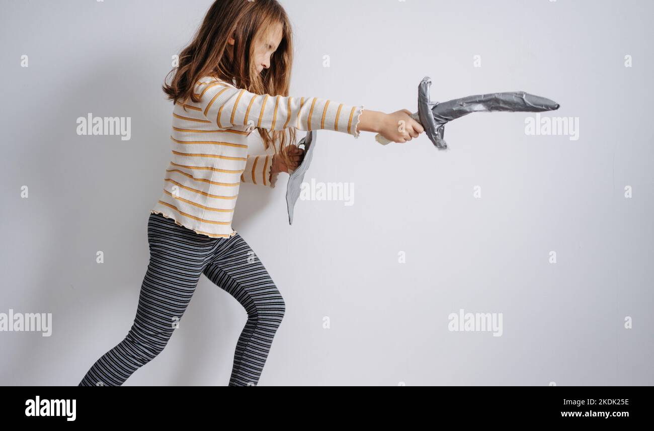 Determined lunging girl posing with self-made toy paper sword and ...