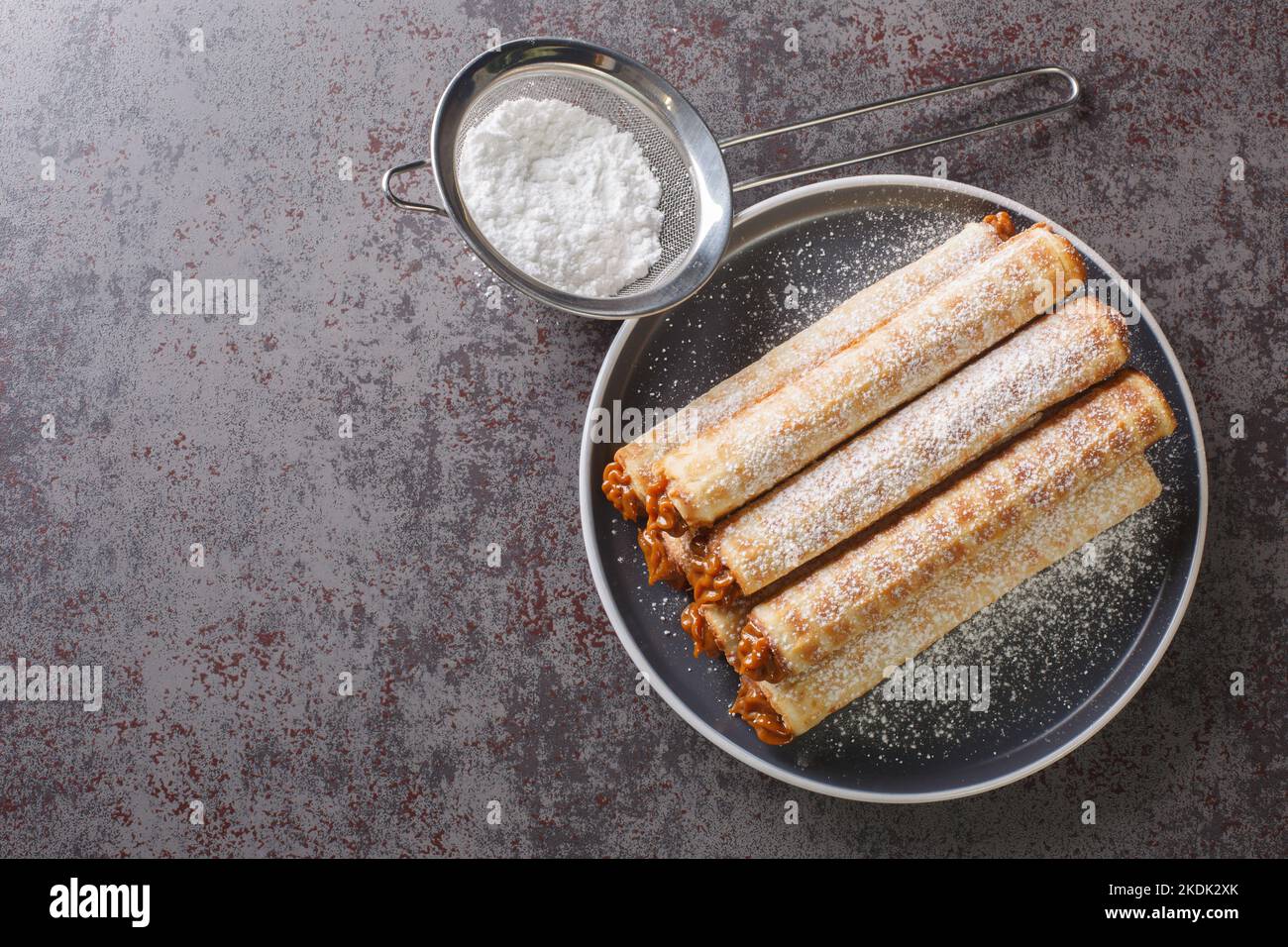 Waffle tubule with boiled condensed milk closeup on plate on the table ...