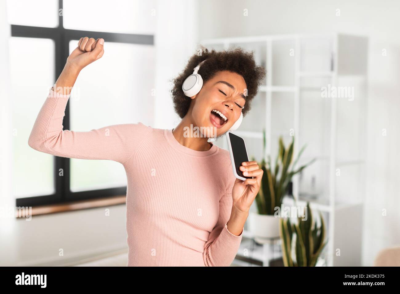 Glad millennial african american lady in wireless headphones sings song ...