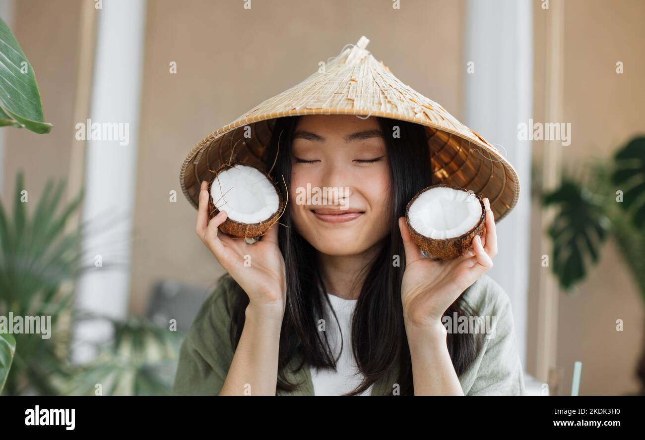 Fashion. Asian woman in summer clothes with coconut in tropical nature ...