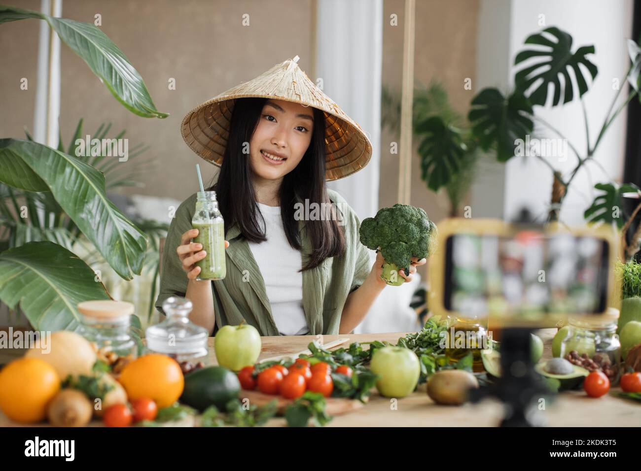 Asian female cooking vlogger in traditional conical hat live-streaming ...