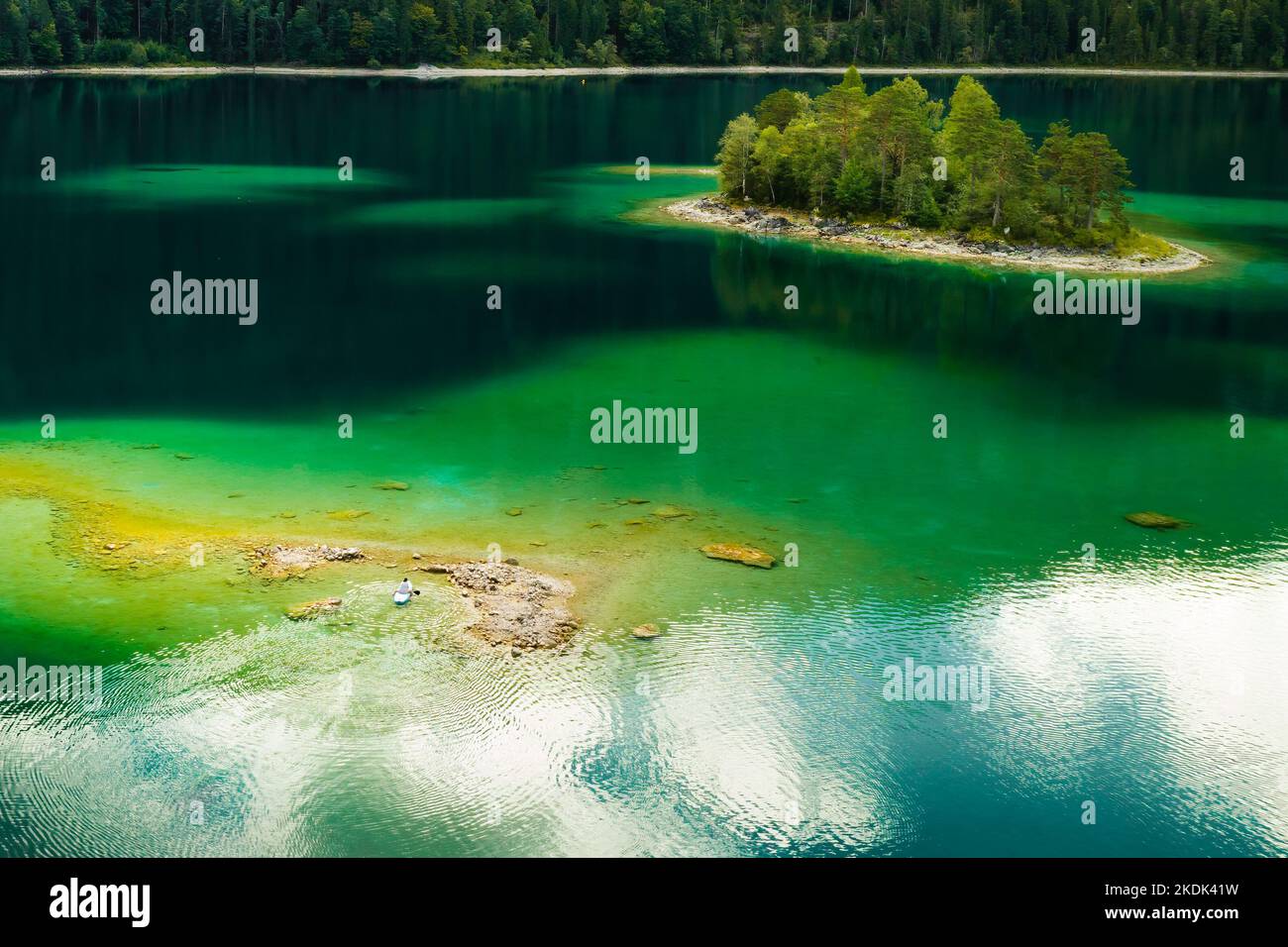A small island with trees in the middle of the lake with transparent ...