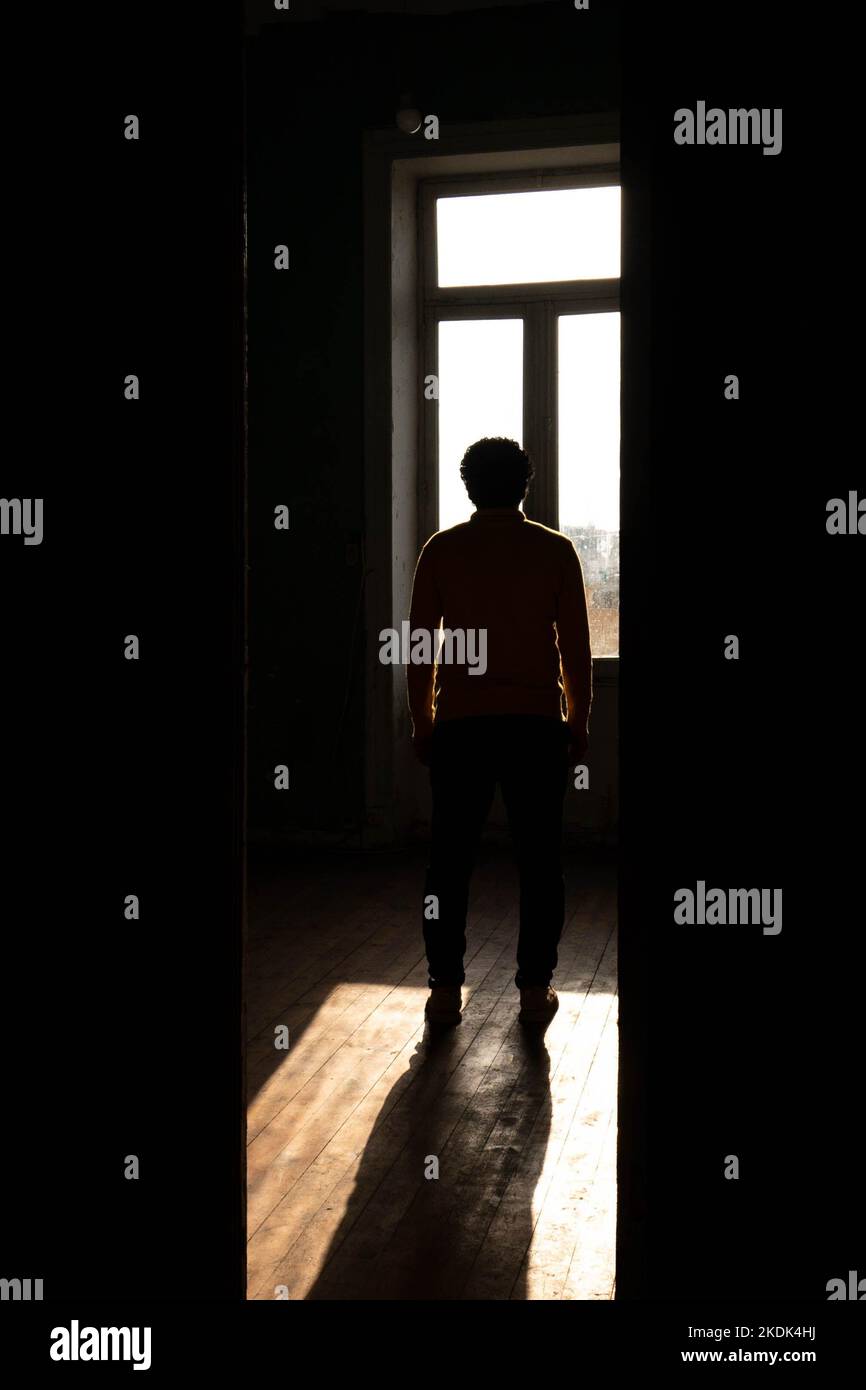 Sun sending its rays through a window throwing its shadows on a man ...