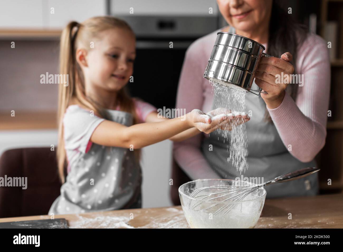 Happy caucasian little granddaughter and elderly grandmother prepare ...